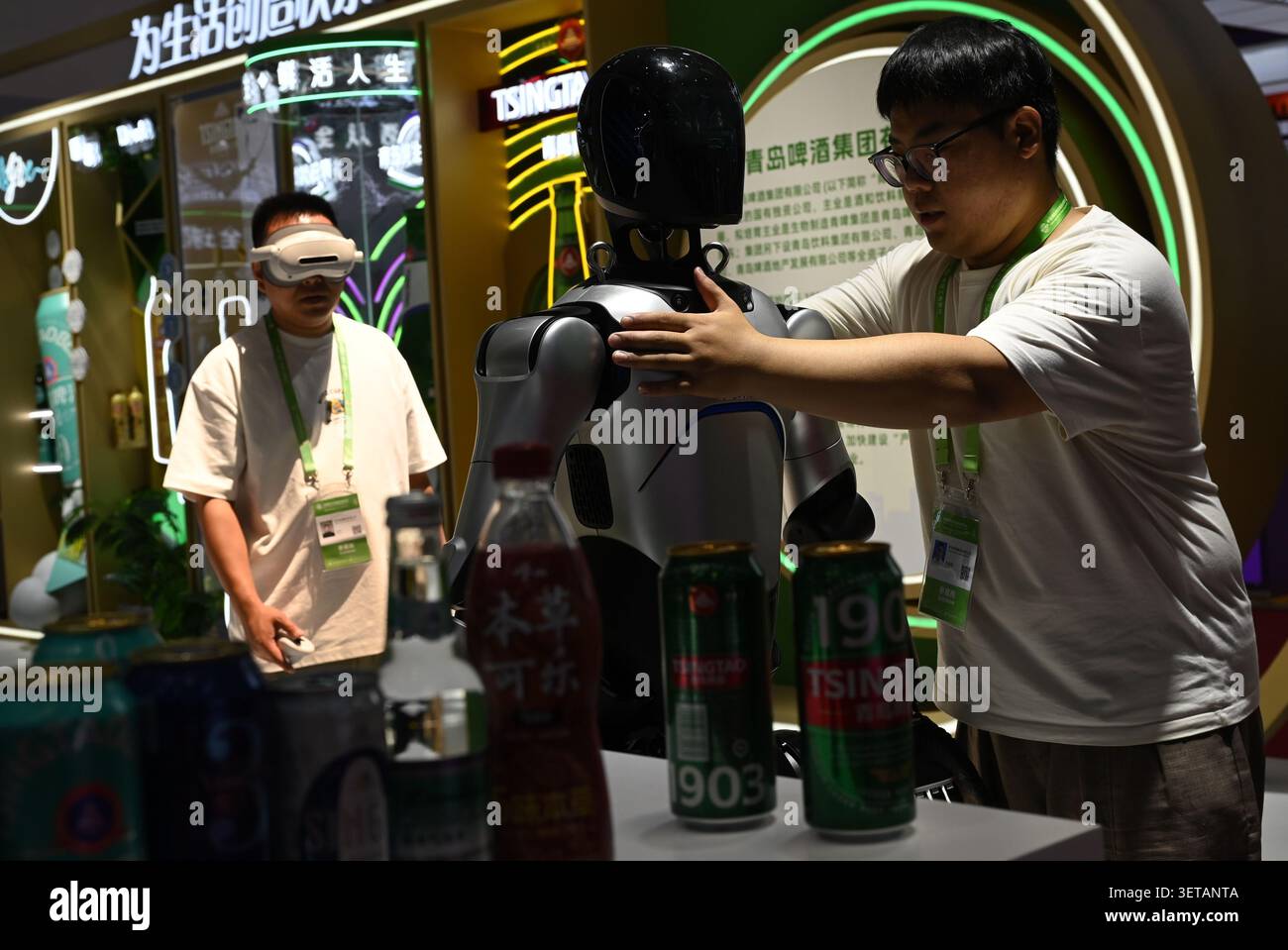 22 June 2026, China, Peking: A man wearing VR goggles stands next to a ...