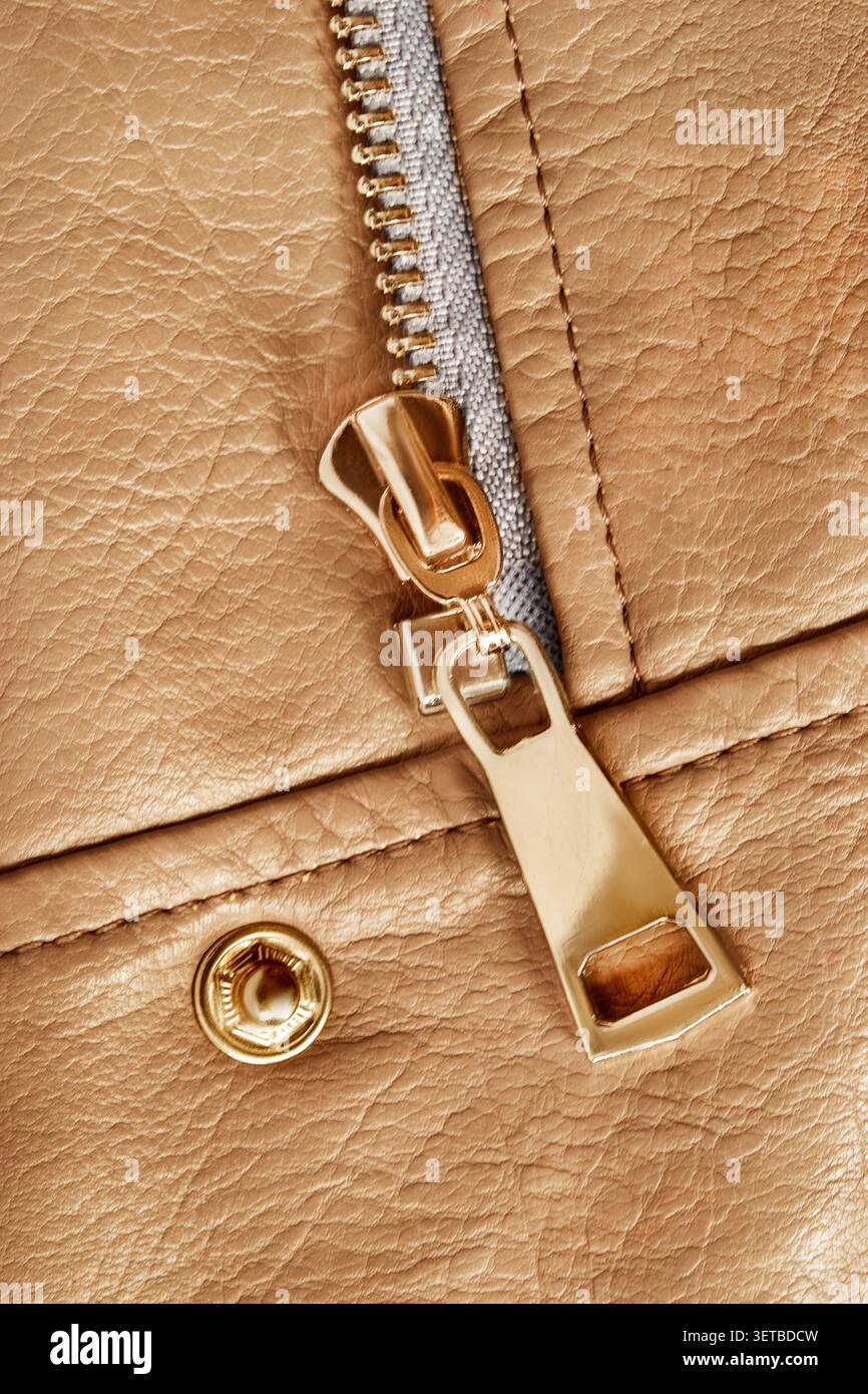 Golden zip slider and snap button on beige leather jacket closeup Stock ...