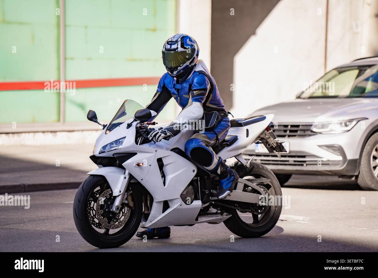 A side profile view of a biker maneuvering a high performance white ...