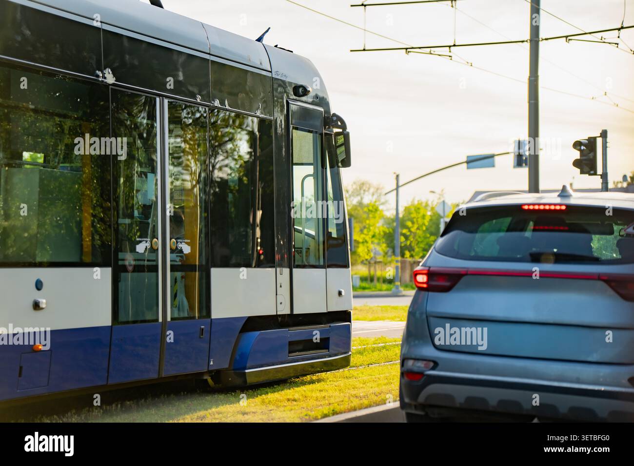 Side view of a sustainable electric tram moving along green tracks ...