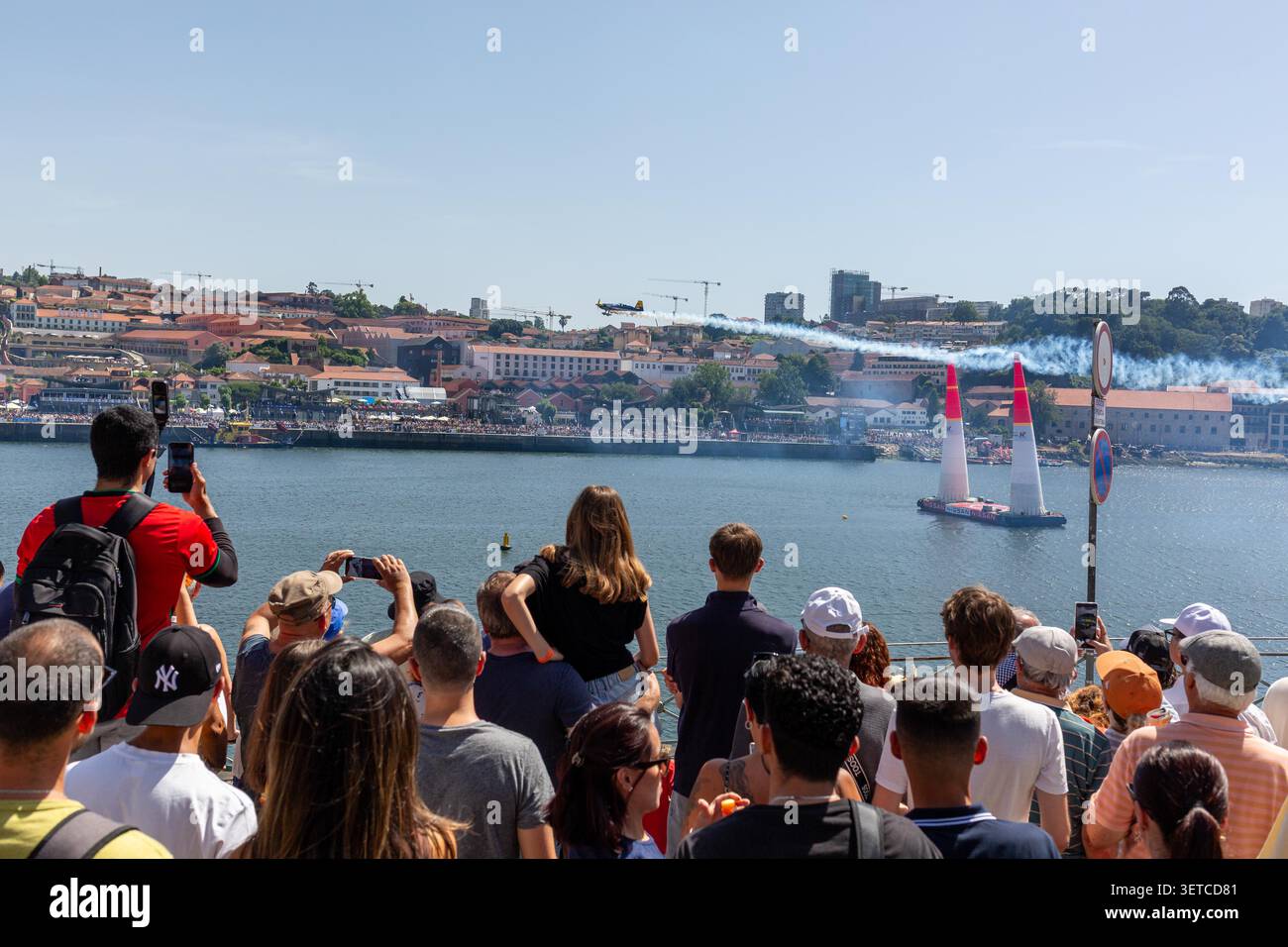 Spectators watch from the riverbank as an aerobatic aircraft flies ...
