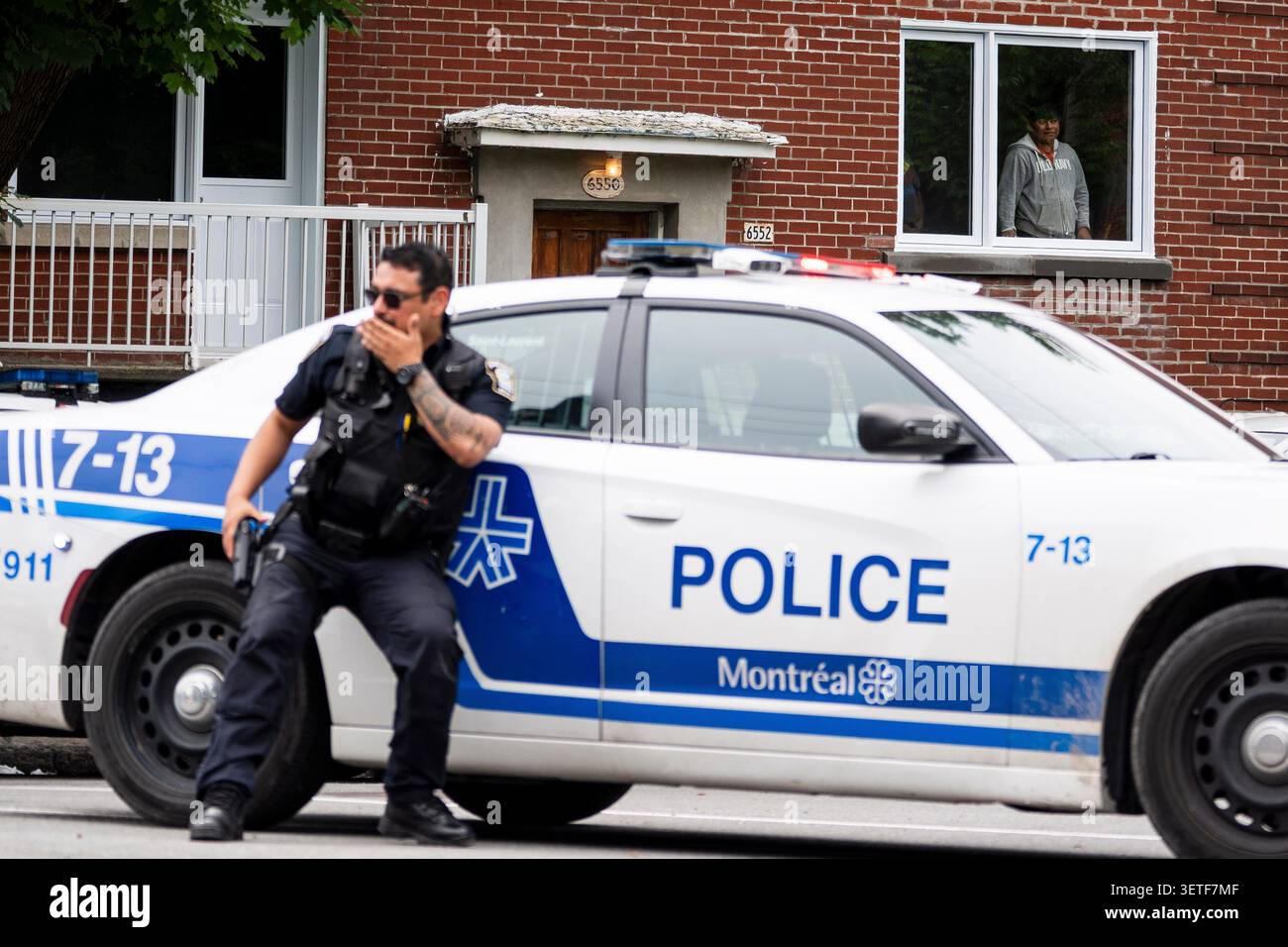 A residents looks on as Montreal police work the scene of a shooting in ...