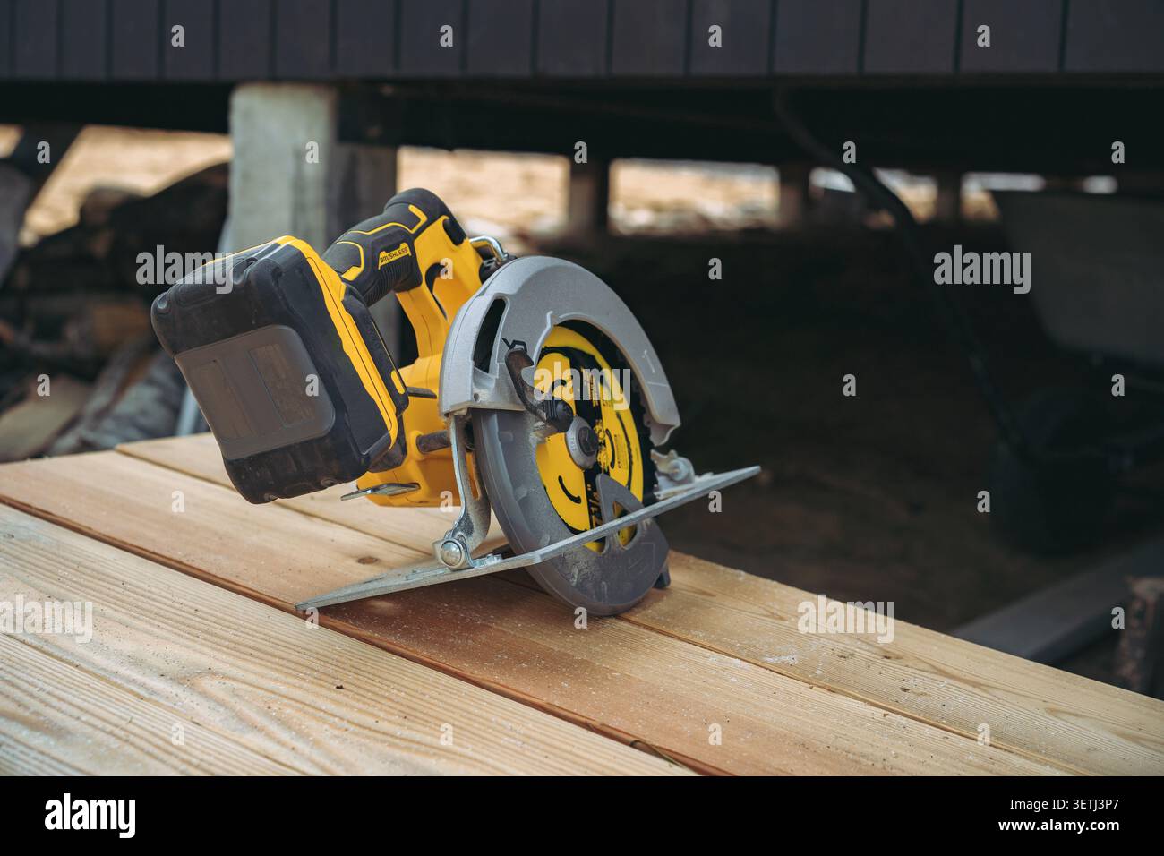A circular saw rests on a stack of larch boards on a countryside ...