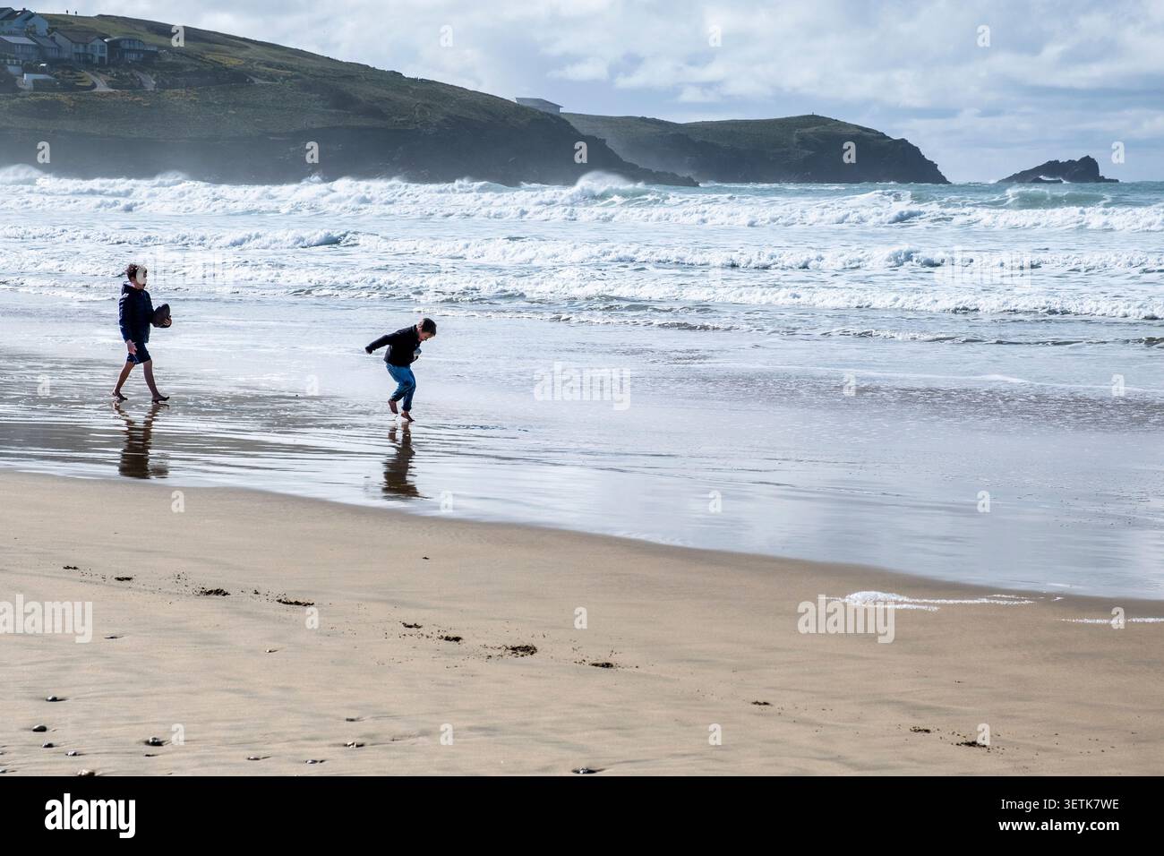 Two young boys walking barefoot on Fistral Beach on the coast of ...