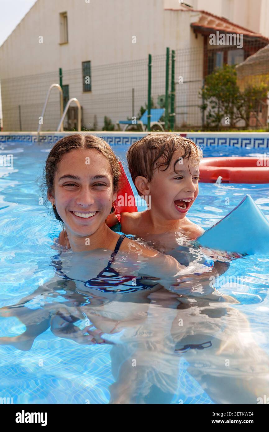 Young woman and boy enjoying playtime in swimming pool, sharing happy ...