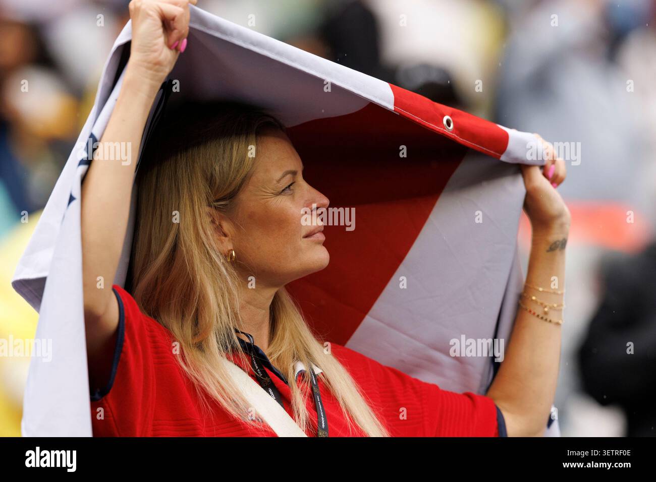 An England fan shields herself from the rain before the start of the of ...