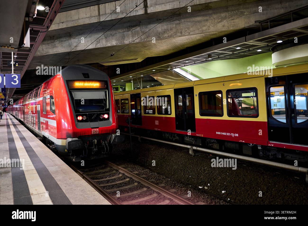 A regional train and a commuter train sit at a standstill at a train ...