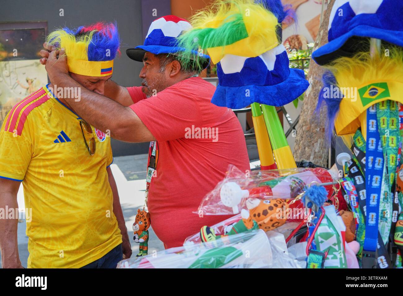 A vendor helps a Colombia fan try on soccer-themed fan gear at a street ...