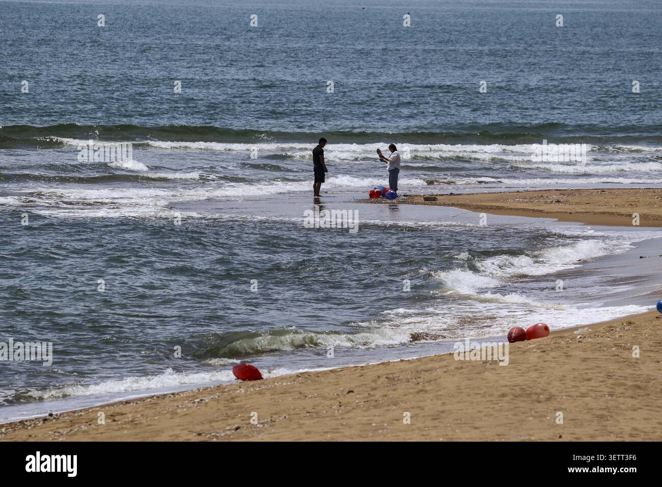 Tourists stroll along the shoreline of Lingshan Bay in Qingdao, east ...