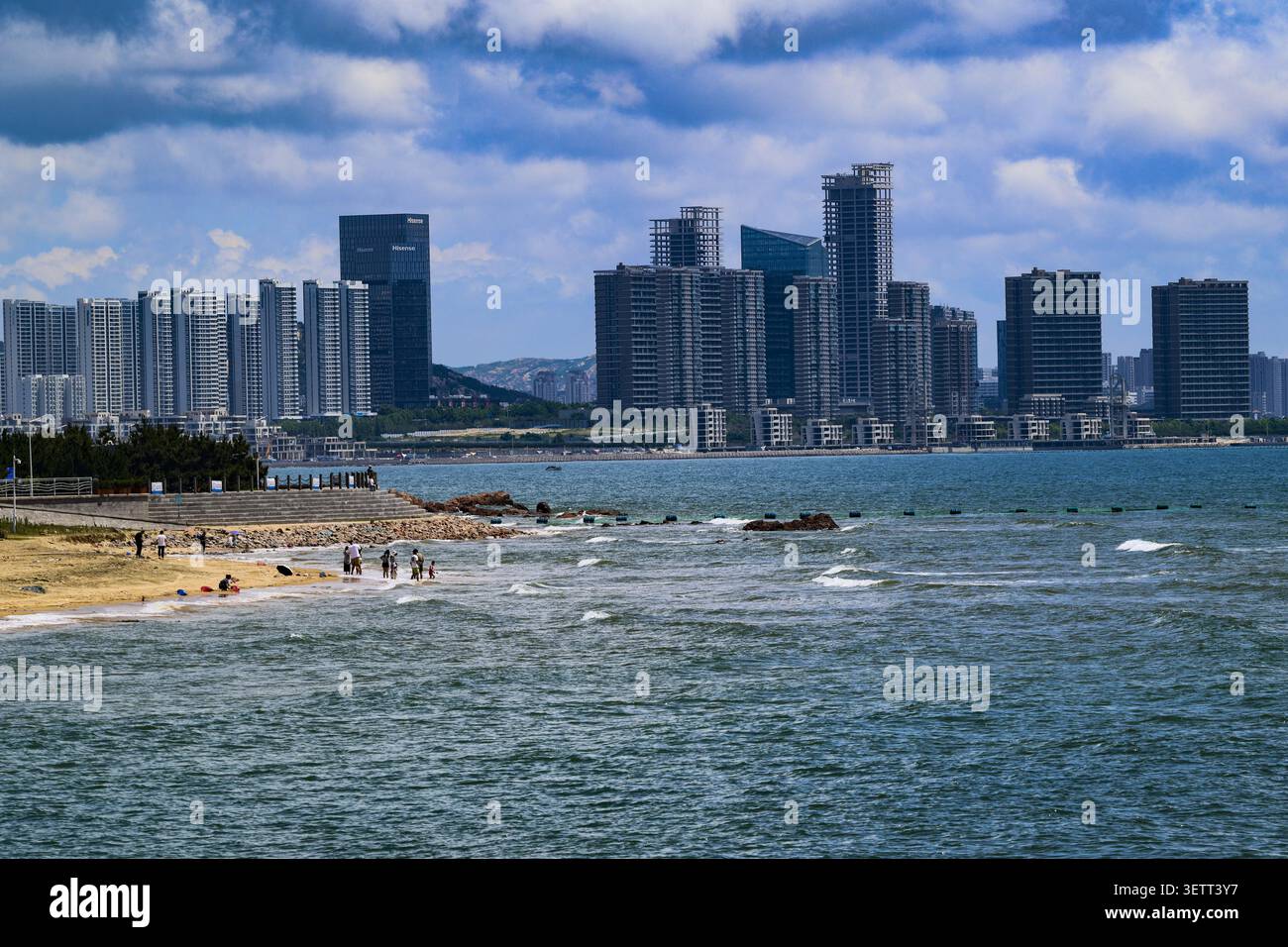 Tourists stroll along the shoreline of Lingshan Bay in Qingdao, east ...