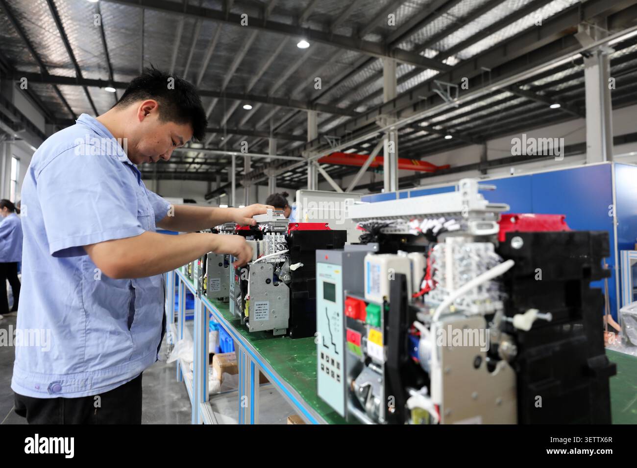 Workers assemble intelligent switch devices at a manufacturing ...