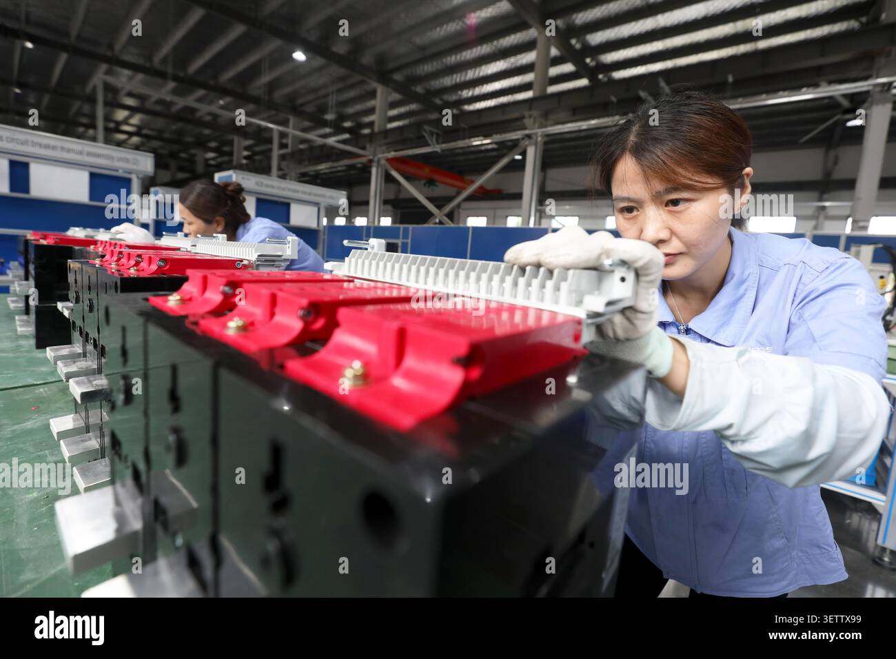 Workers assemble intelligent switch devices at a manufacturing ...