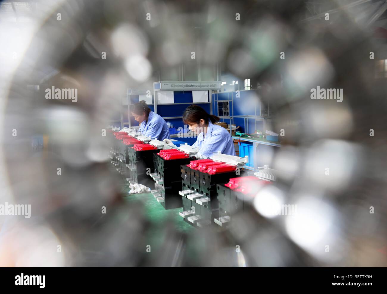 Workers assemble intelligent switch devices at a manufacturing ...
