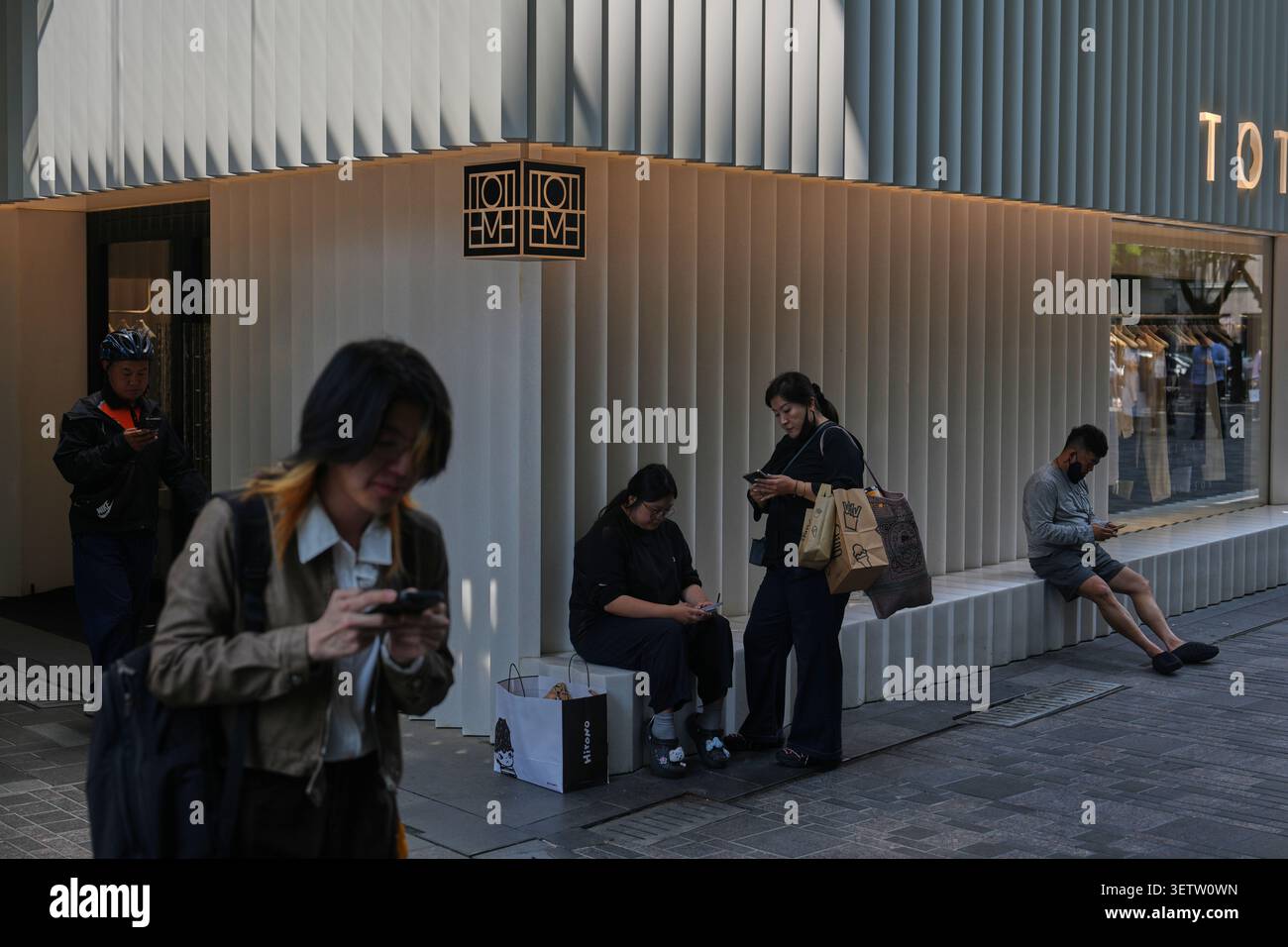 Women with their purchased goods rest outside a fashion boutique at an ...