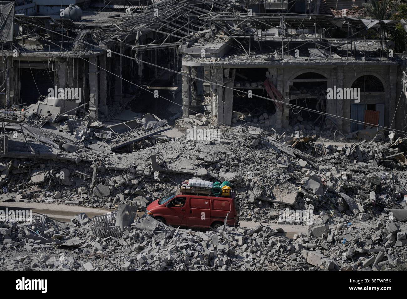 Residents drive past buildings destroyed in previous Israeli airstrikes ...