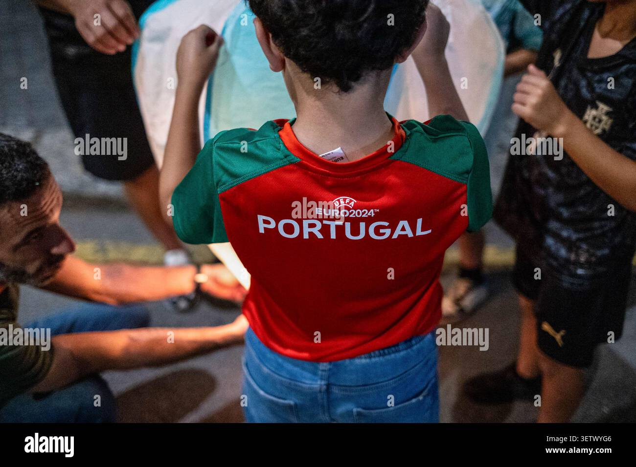 A young boy wearing a Portuguese national team shirt helps prepare a ...