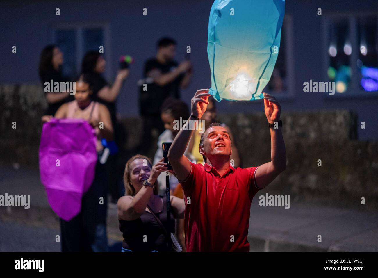 People prepare illuminated paper balloons in the street during the São ...