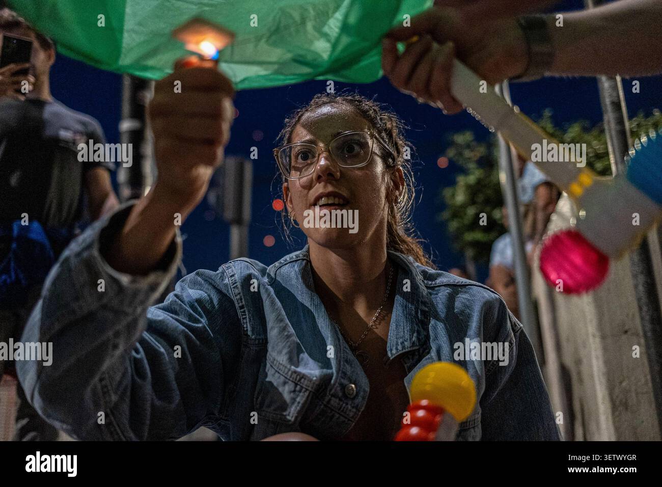 A woman lights a paper balloon during the São João celebrations ...