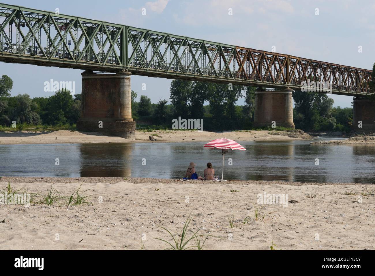 Women relax as they sunbath under the Becca bridge on the Po riverbed ...