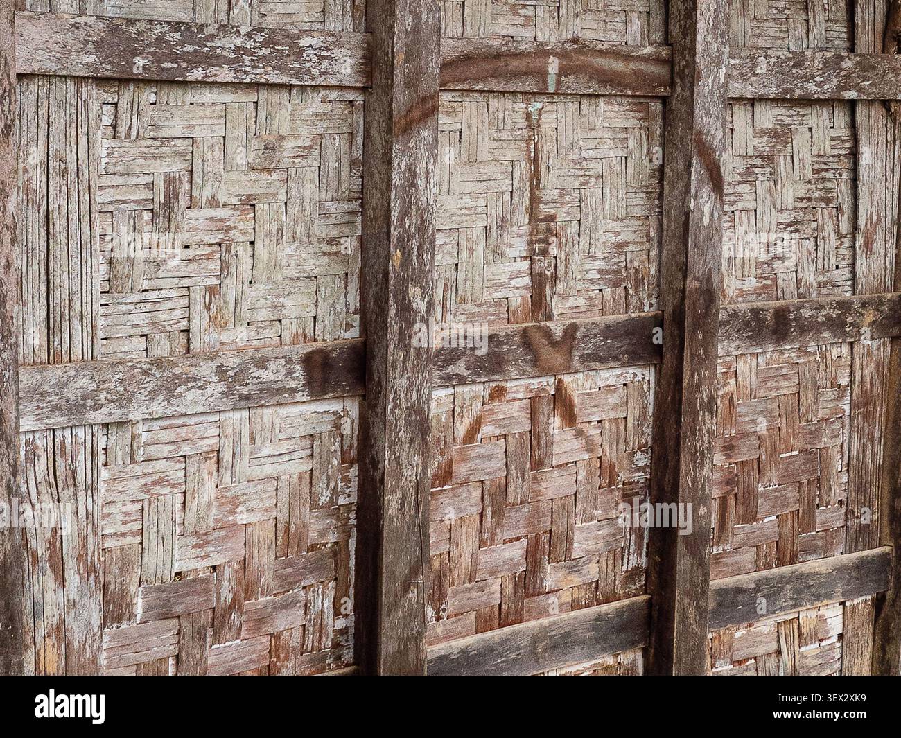 Weathered wooden pillars and woven bamboo wall texture of a traditional ...