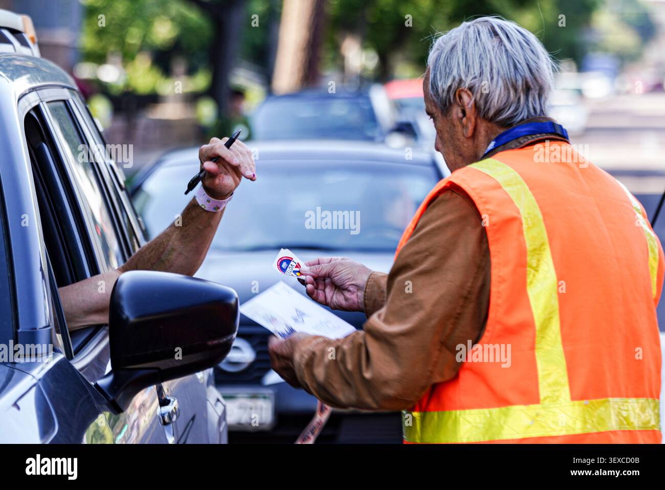 Election Judge Adam Ballinger hands a voter a sticker at a ballot drop ...