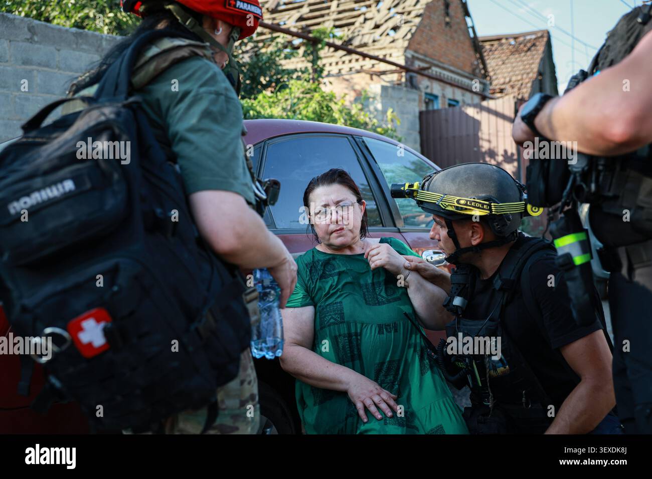 Policemen help a woman after a Russian strike on residential ...