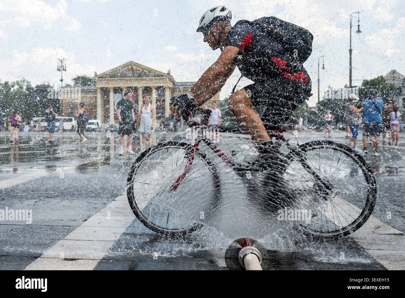 A cyclist rides in front of a police water cannon hose spraying a ...