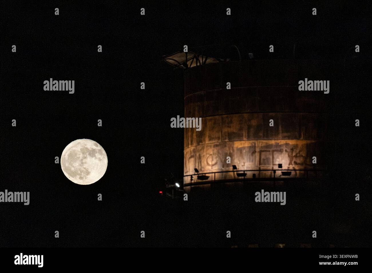 The Strawberry moon is seen rising next to a water tower in, Limassol ...