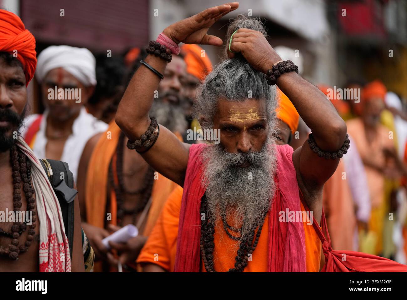 A Hindu holy man ties his hair as he waits in a queue to register for ...