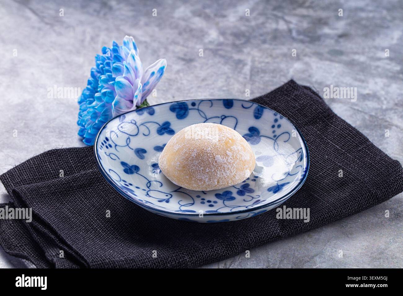 Mochi dusted with powdered sugar sits on blue white ceramic plate ...