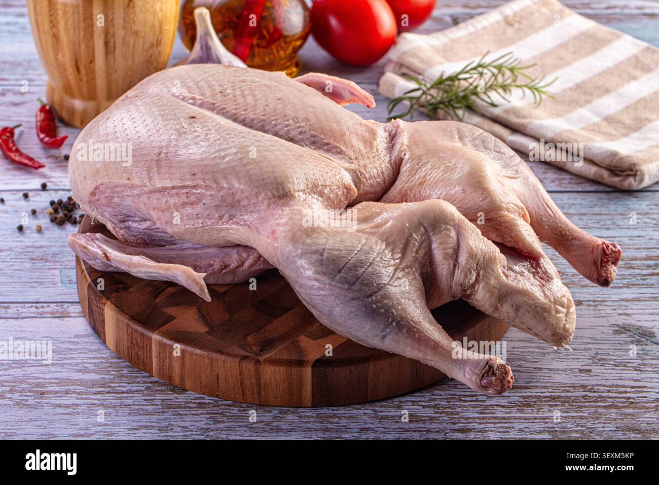Raw duck centered on wooden board surrounded by rosemary garlic chili ...