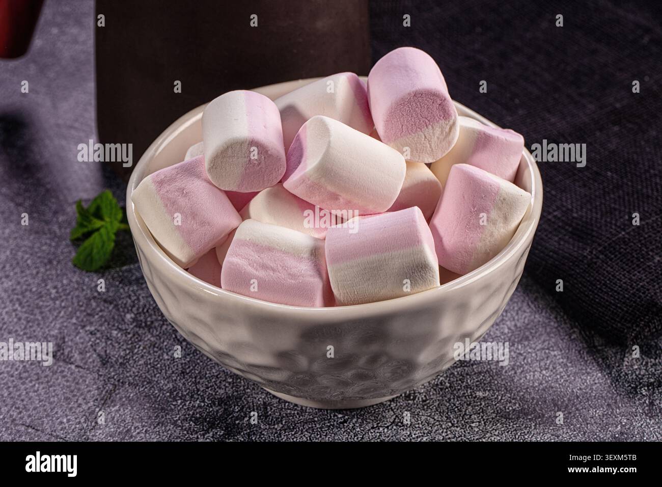 Pink white marshmallows piled in textured ceramic bowl with mint leaf ...