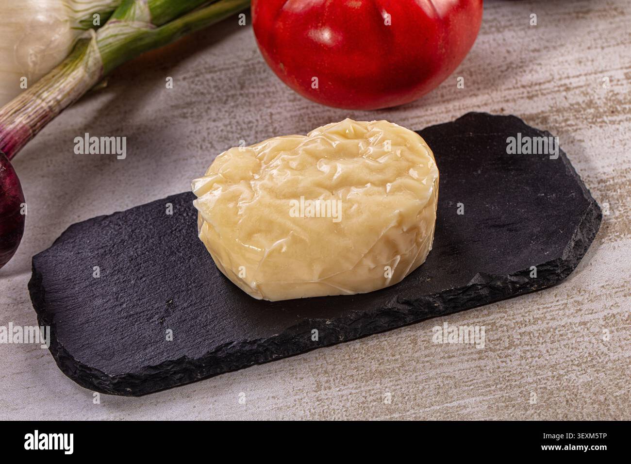 Block of halloumi cheese placed on dark slate serving board surrounded ...