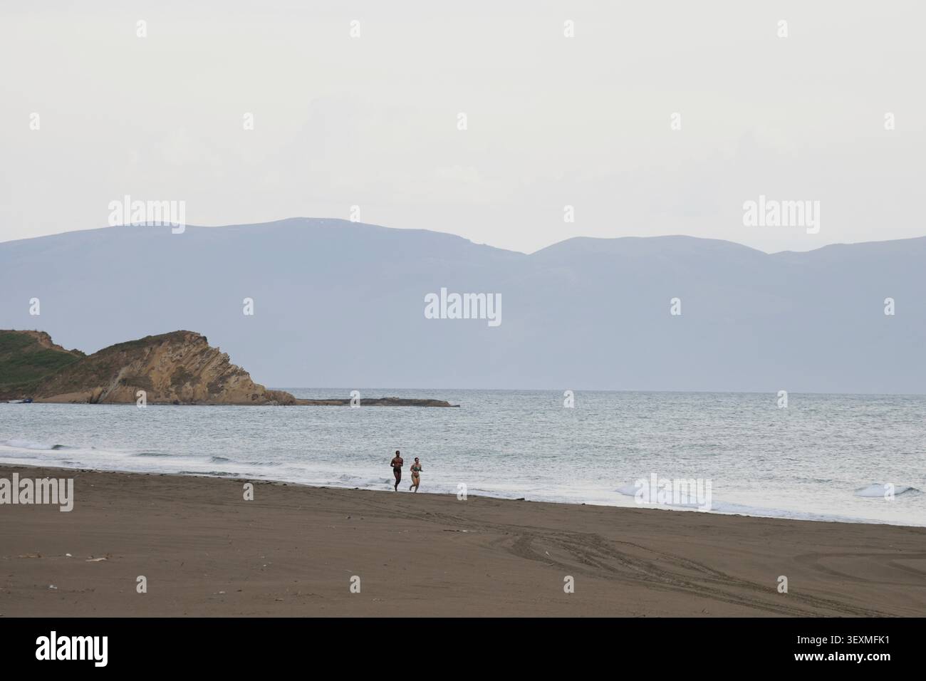 A couple run in Narta lagoon area, western Albania, Tuesday, June 30 ...