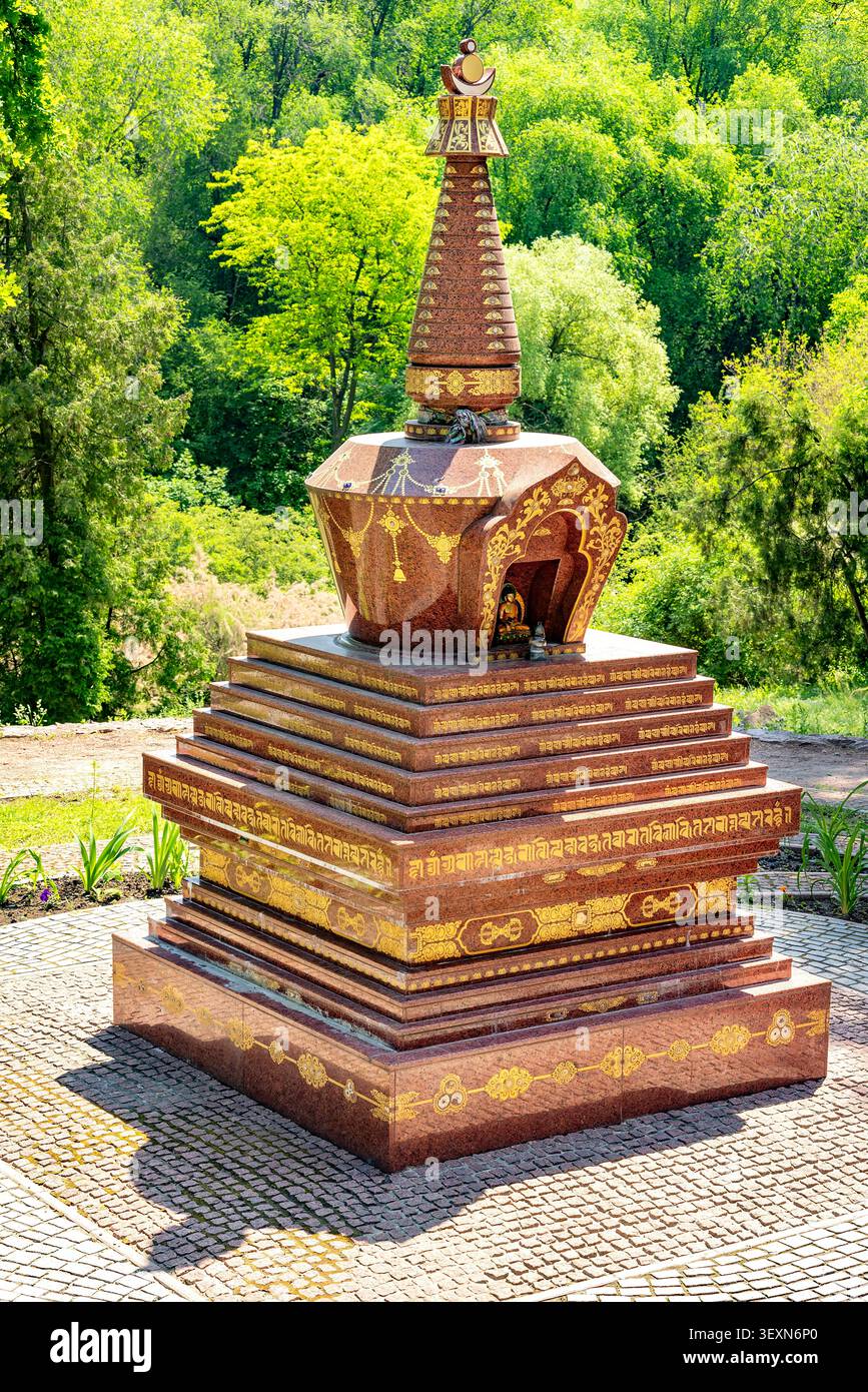 A stupa is situated in an open space surrounded by trees and greenery ...