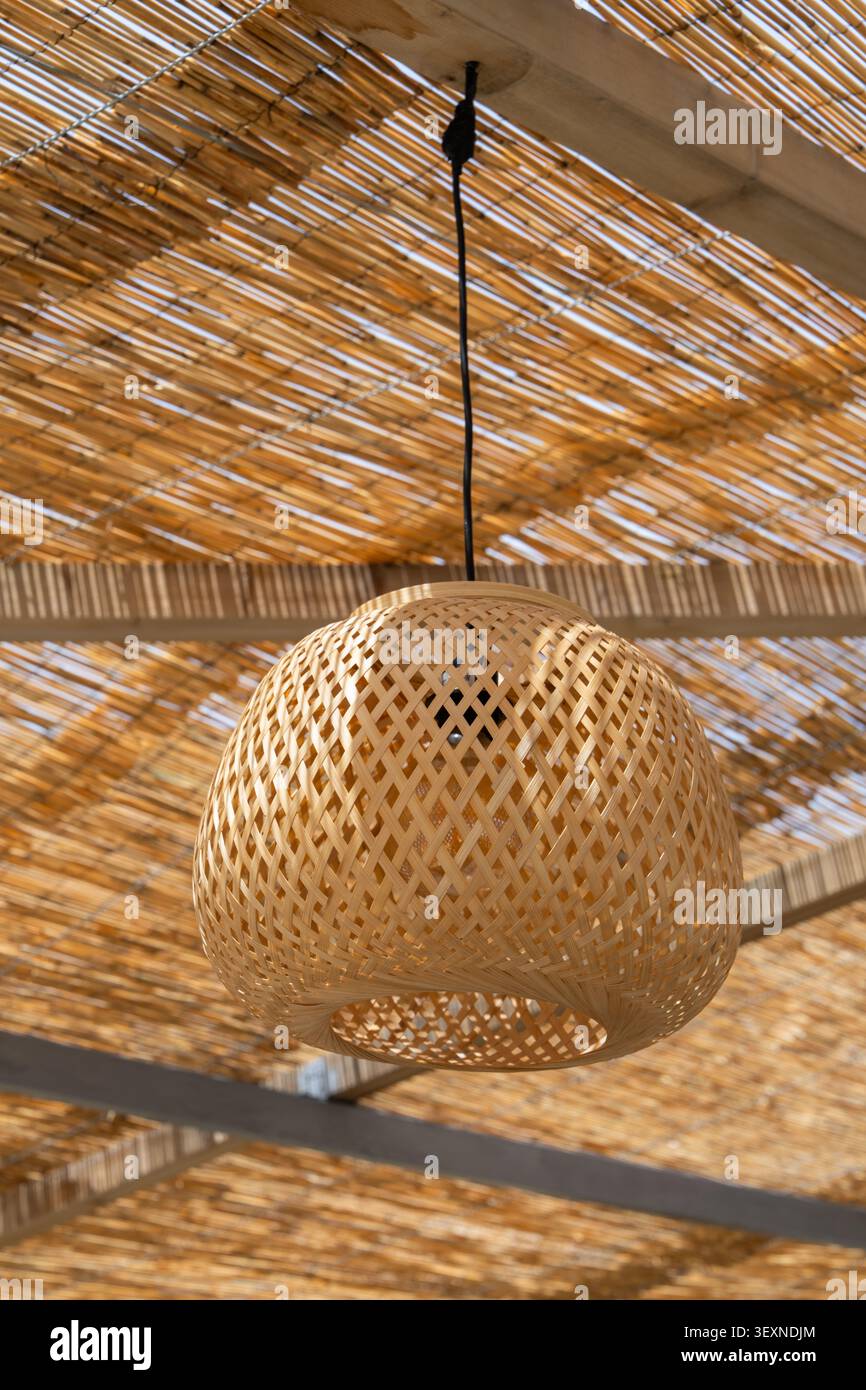 Close up of woven pendant lamp beneath traditional thatched roof at ...