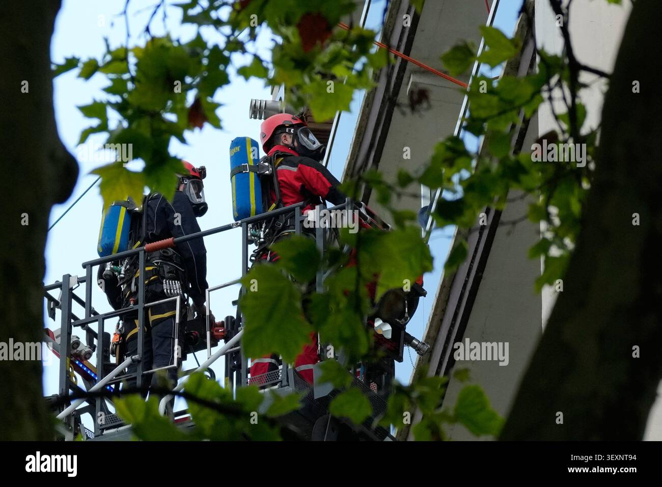 Emergency workers search the upper floors after an apartment block fire ...