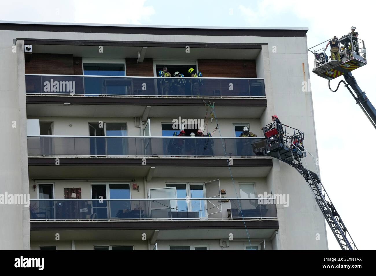 Emergency workers search the upper floors after an apartment block fire ...
