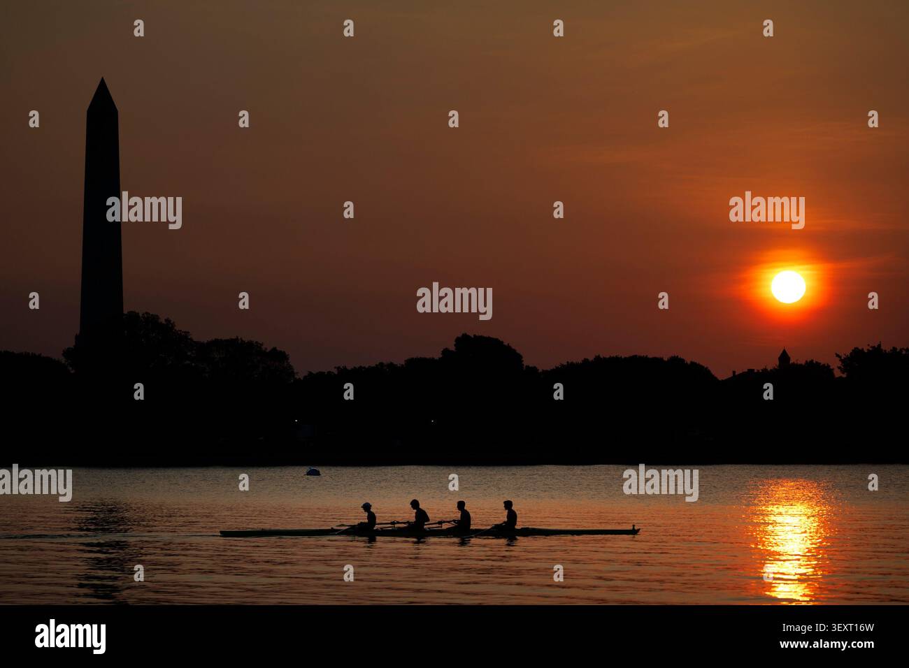 Rowers pass by in the Potomac River as the sun rises near the ...