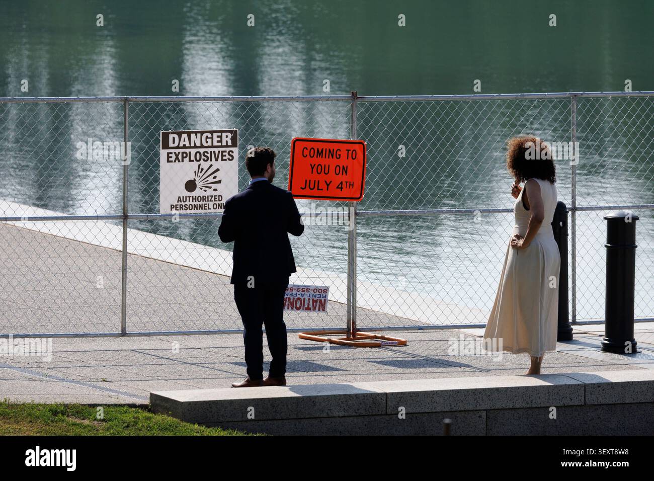 Visitors glance at warning signs posted on a security fence at the ...