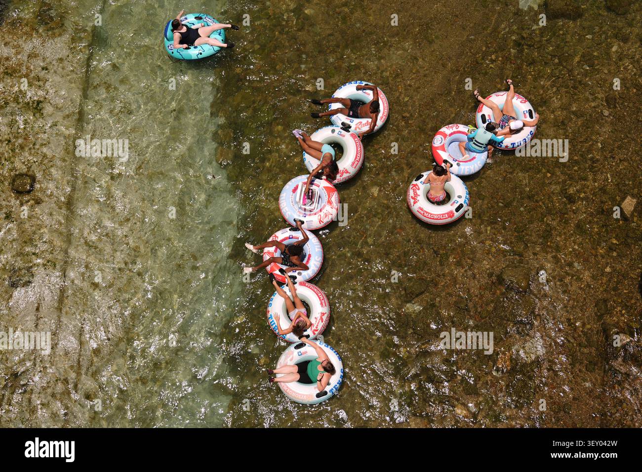 Tubers chain together as they float along the cool waters of the Comal ...