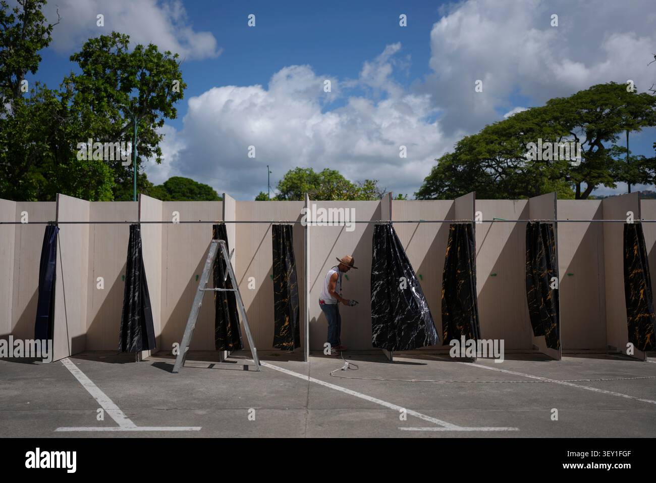 A worker sets up portable showers at Francisco de Miranda Park in ...