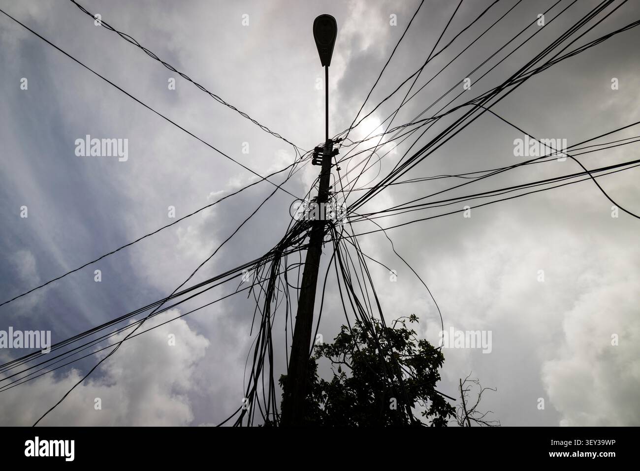 FILE - A utility pole with loose cables towers over the home of ...