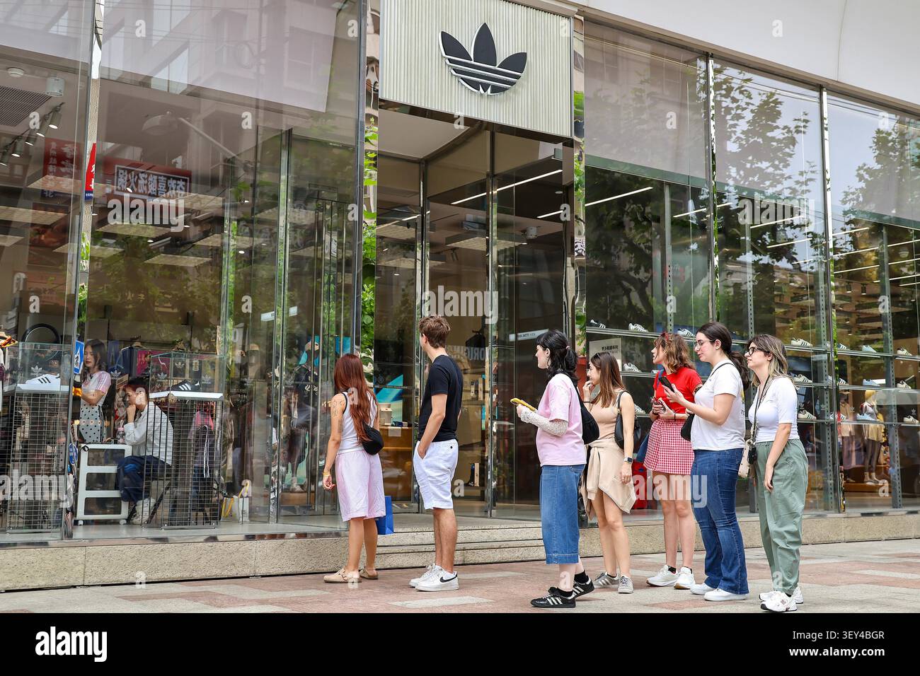 Foreign tourists watch a livestream host promoting products outside an ...