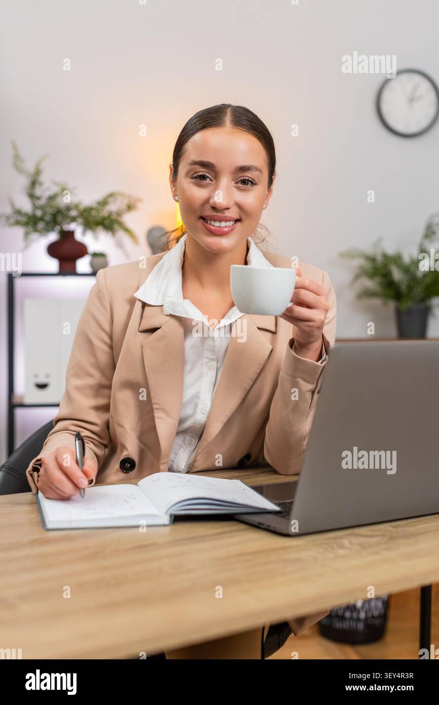 Young businesswoman at home office drinks coffee slowly reads plan in ...