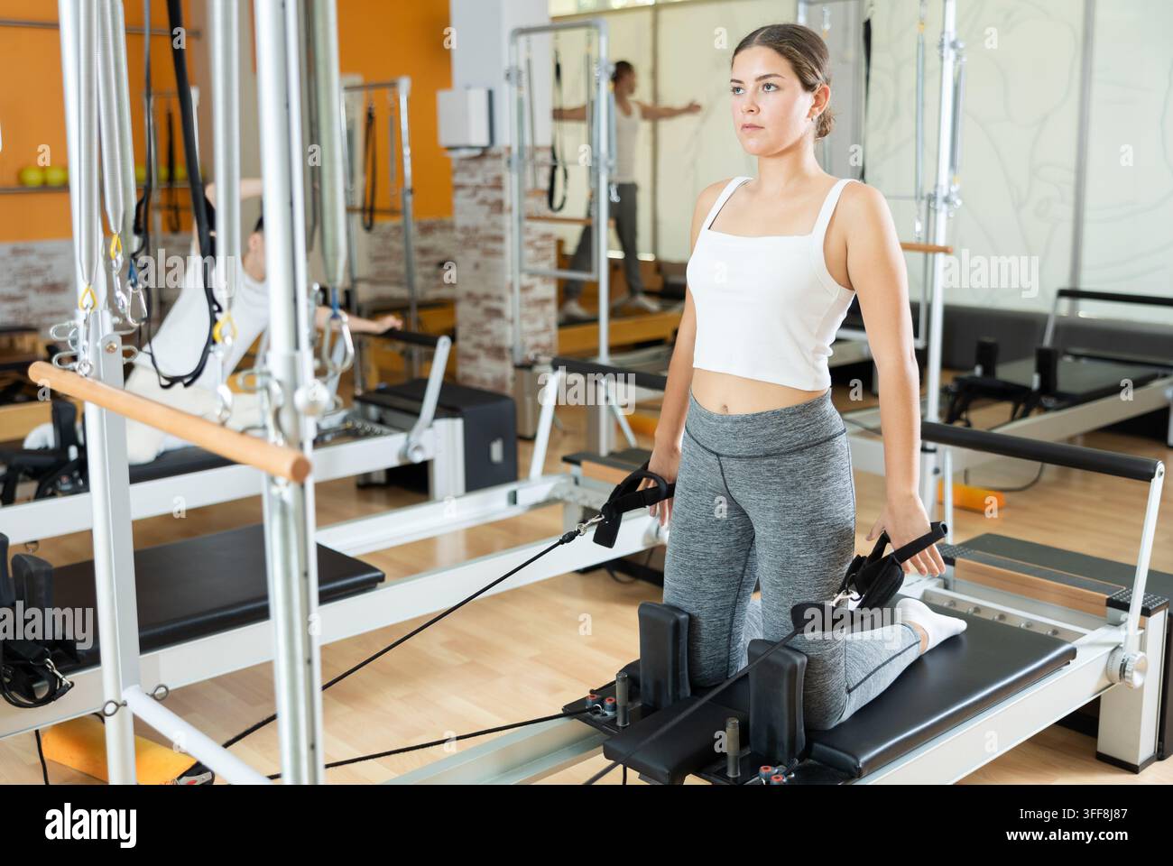 Girl In Gym With Help Of Reformers Equipment Performs Workout To