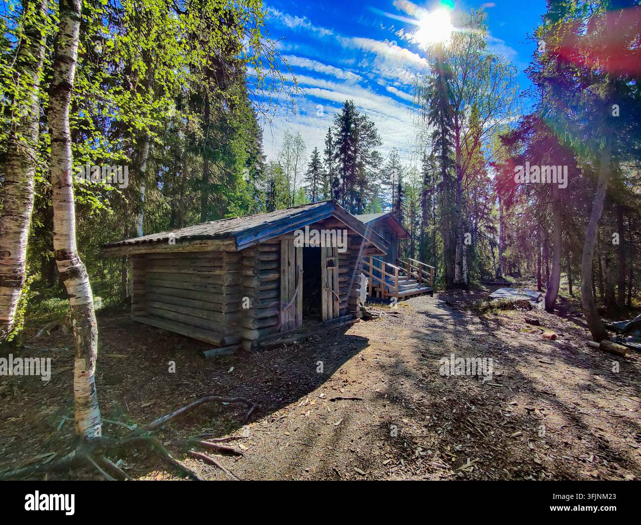 A rustic wooden hiking cabin stands surrounded by green trees and a ...