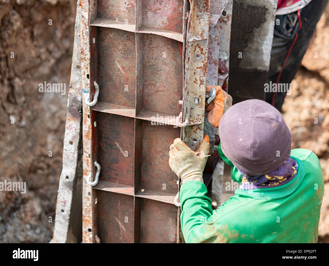 Worker installing and fastening metal formwork for reinforced concrete ...