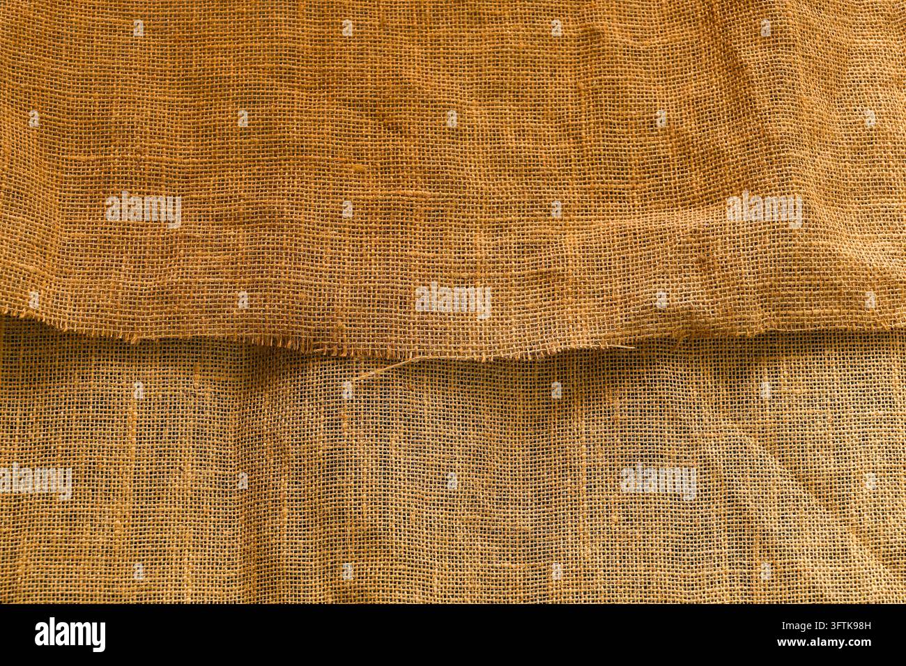 A brown burlap fabric texture with coarse woven fiber, folded surface ...