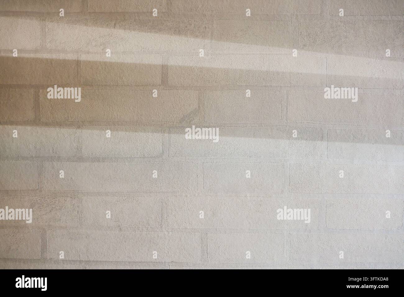 A white concrete block wall with subtle horizontal shadow, weathered ...